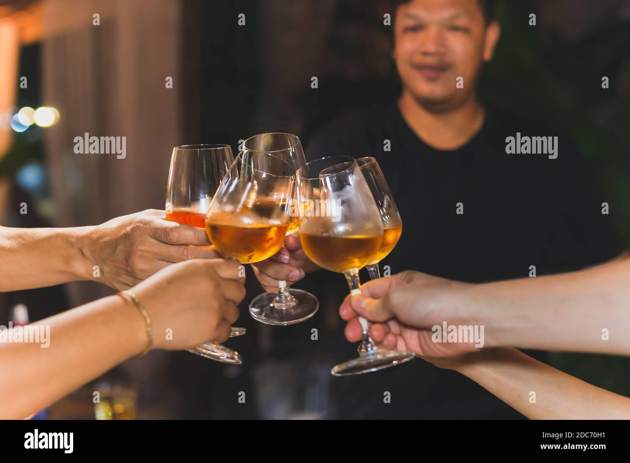 Shot in high iso with low light group of friends toasting white wine ...