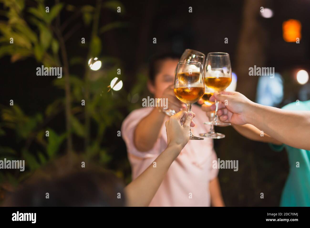 Shot in high iso with low light group of friends toasting white wine ...