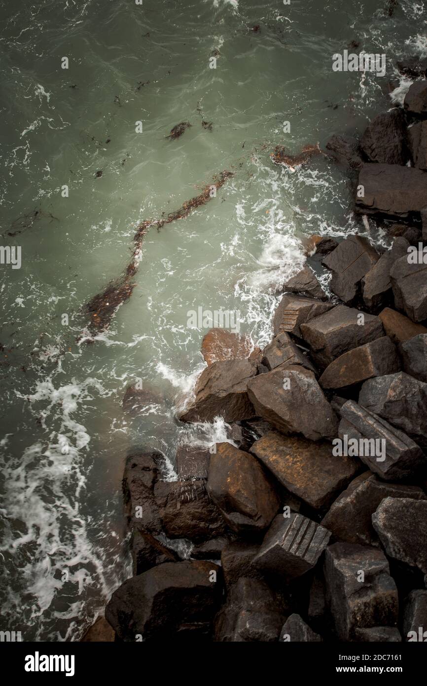 rocks crashing on the shore against rocks or sea defences shot from ...