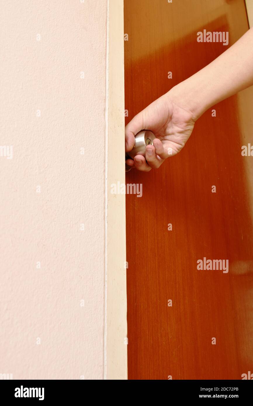 hand twisting silver knob to opened wooden door in home Stock Photo - Alamy