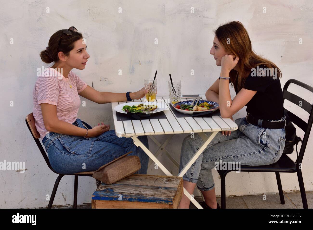 Two attractive young women eating lunch at single table, old town ...