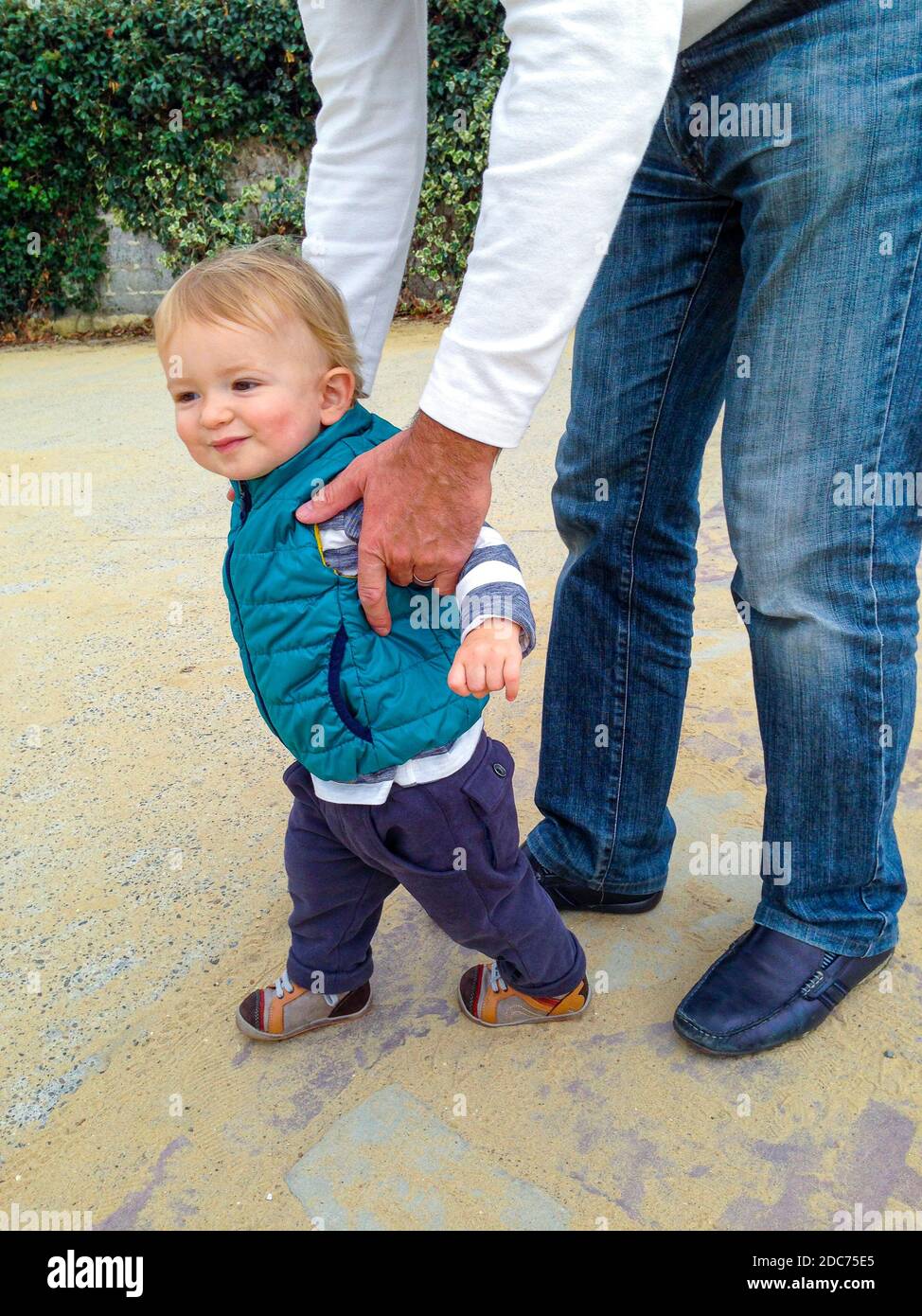 Father guiding his son with the first steps outside. Baby learning to ...