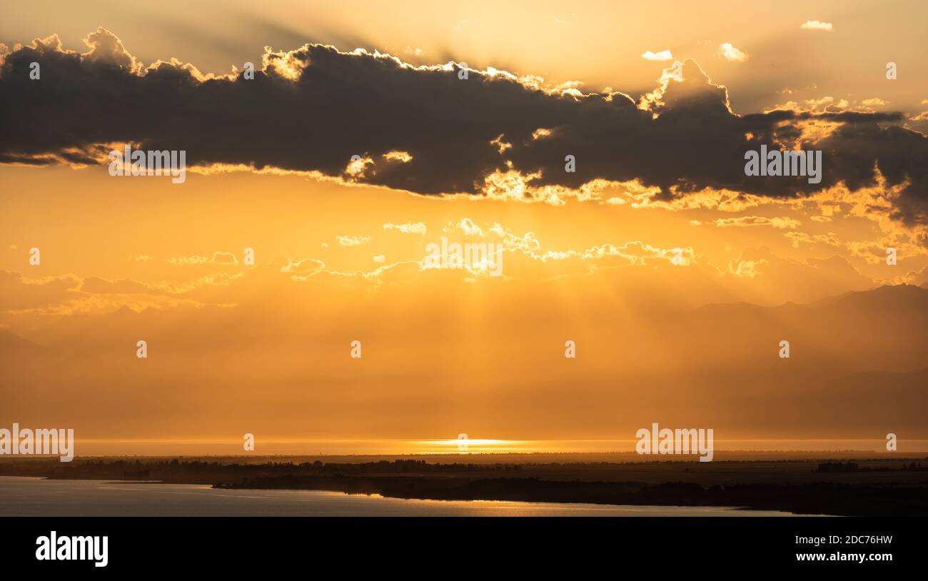 Sun beams on Issyk Kul Lake at sunset near Karakol in Kyrgyzstan Stock ...