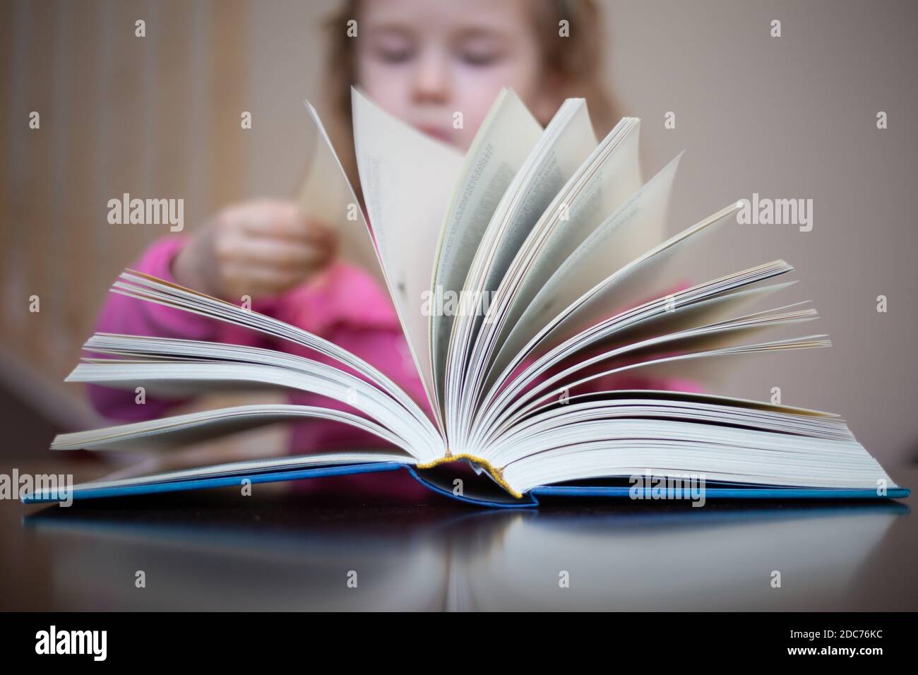 Little blonde girl reading and doing homework Stock Photo - Alamy