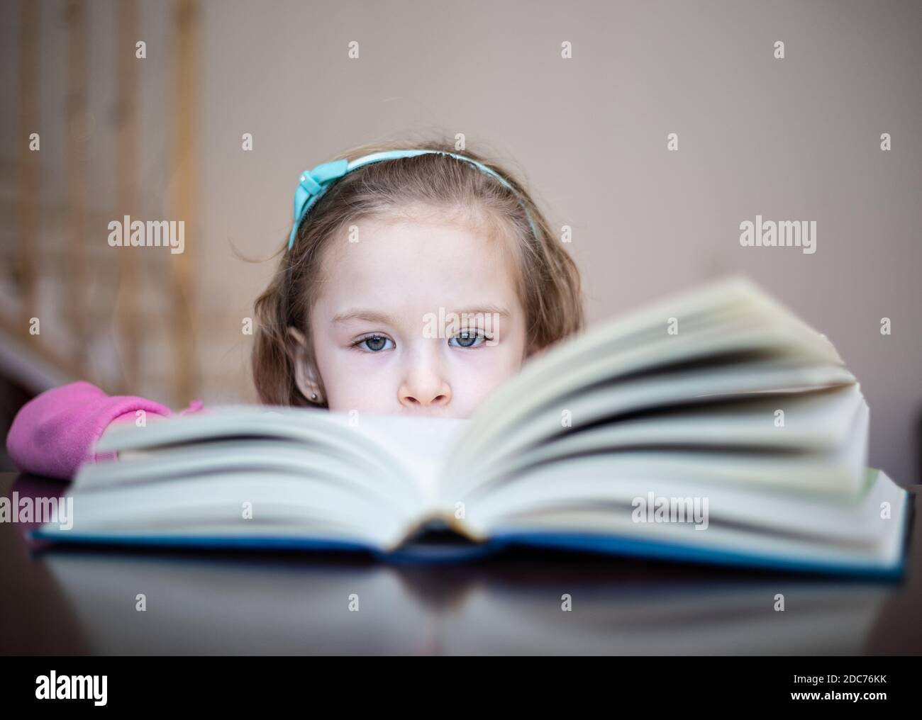 Little blonde girl reading and doing homework Stock Photo - Alamy