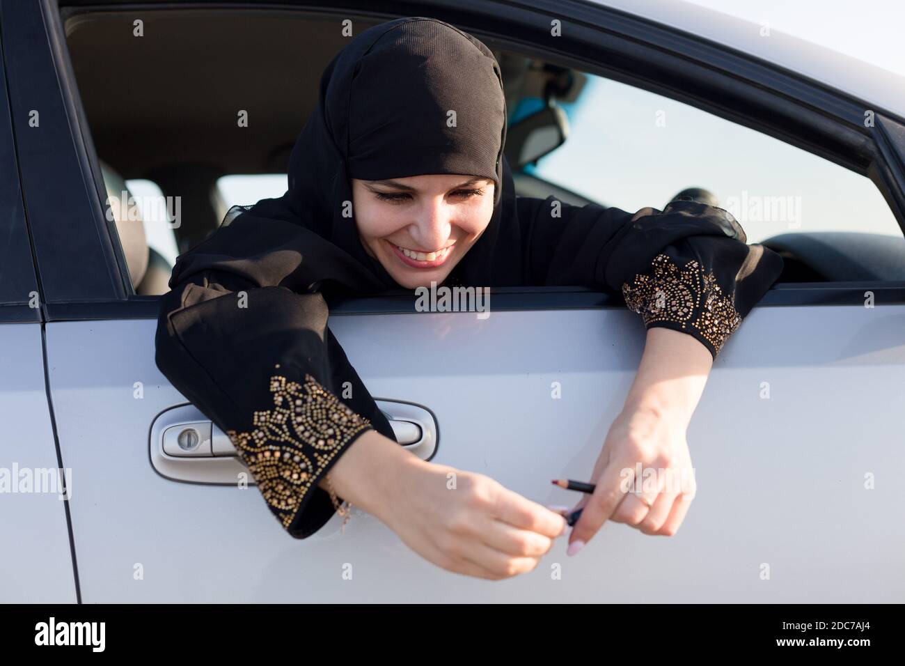 Islamic woman driver sharpens lip pencil while sitting in car Stock ...