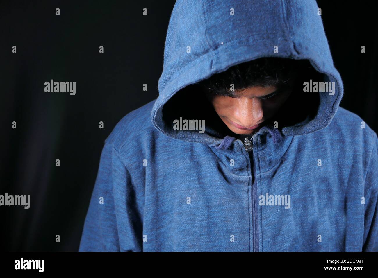 sad man in hood looking down isolated on black Stock Photo - Alamy