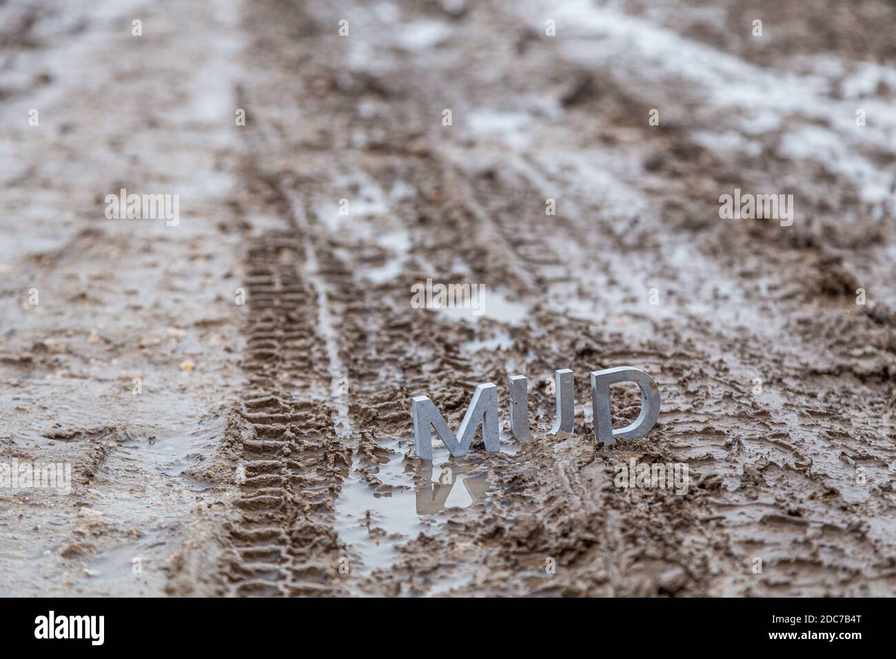 the word mud composed of silver metal letters on wet dirt surface with ...