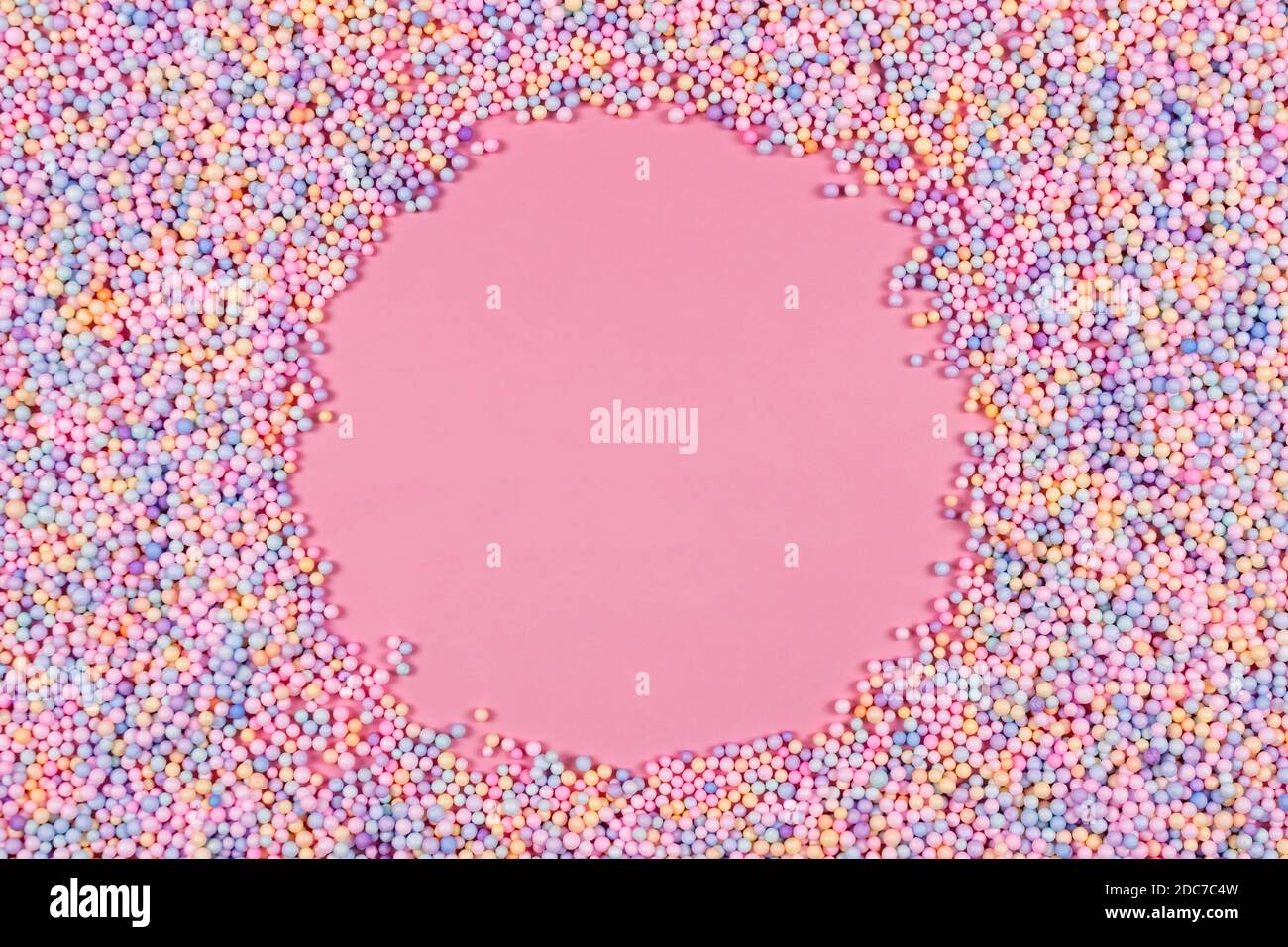 Round frame made of pastel color balls on pink. Styrofoam or ...