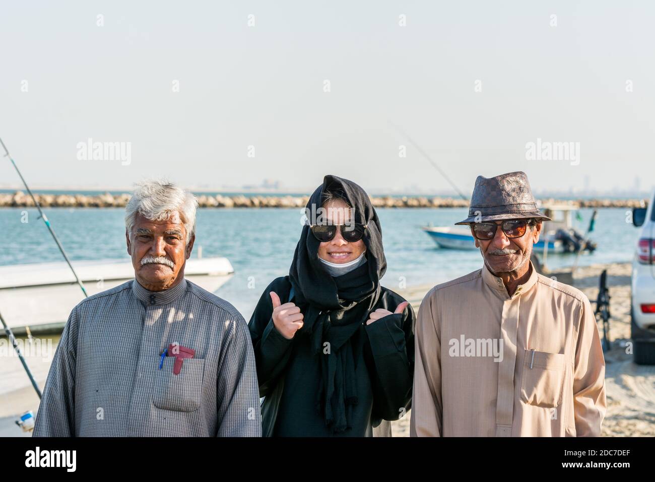 An Asian tourist and two mid-aged Saudi Arabian men at the beach of ...