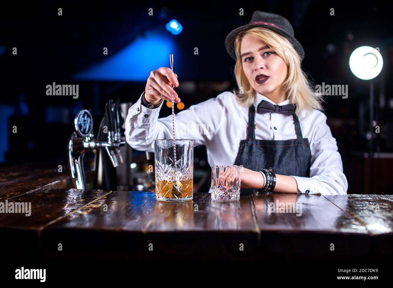 Focused girl bartending pouring fresh alcoholic drink into the glasses behind the bar Stock ...