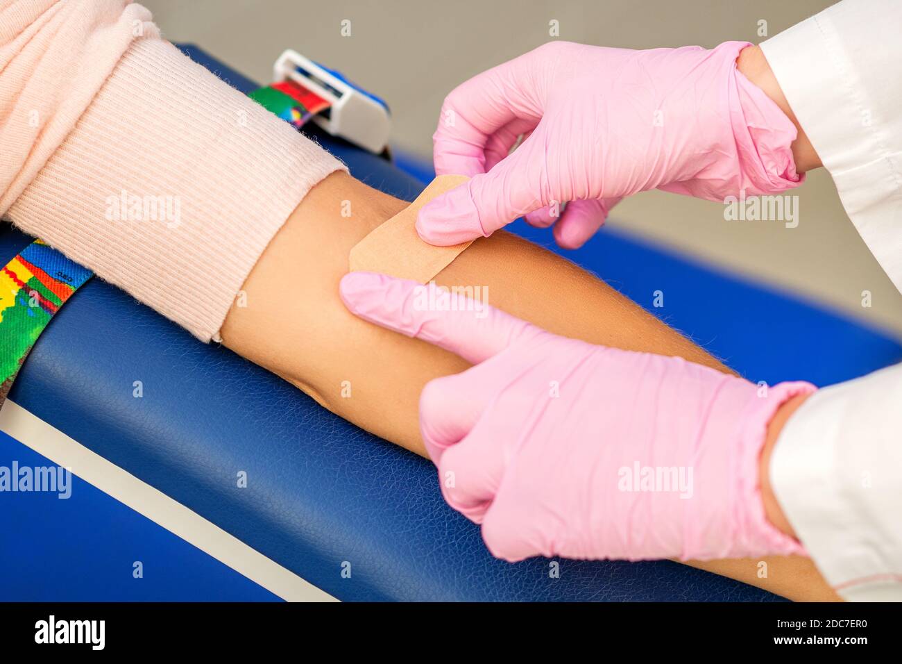 Close up of nurse hand applying adhesive plaster on arm of patient ...