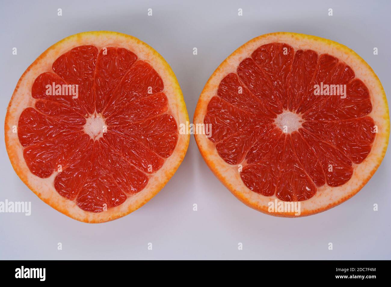 Two halves of a ripe juicy grapefruit, divided into two identical ...