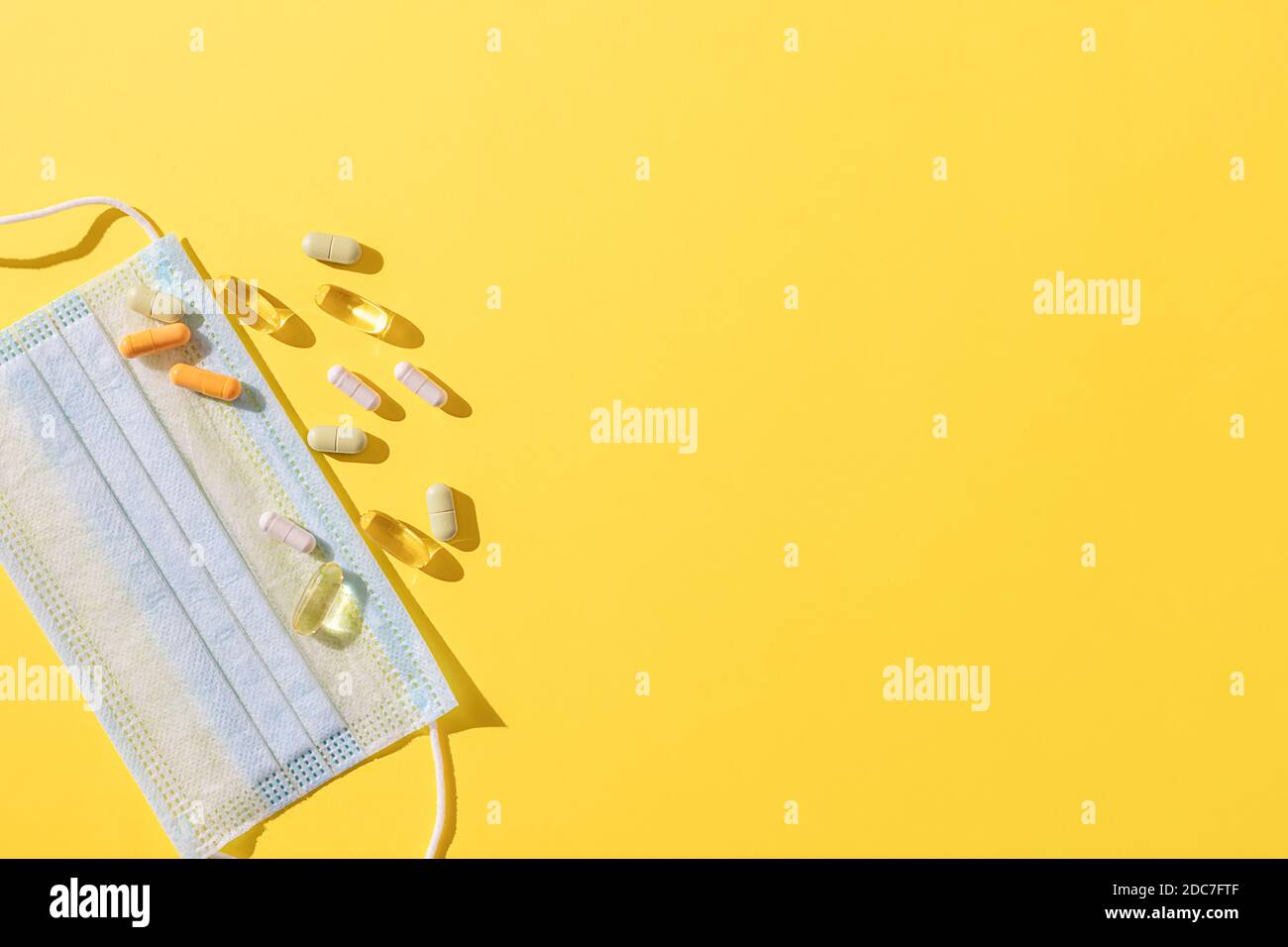 Protective face masks, medicinal pills on a yellow background with ...