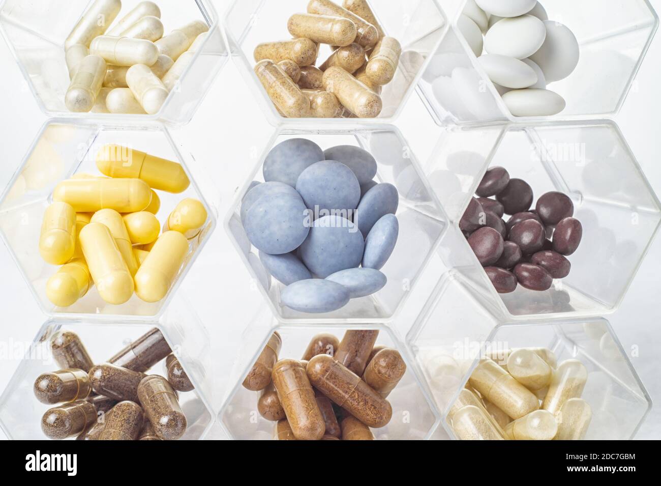 Various medical capsules and tablets in hexagonal transparent jars ...
