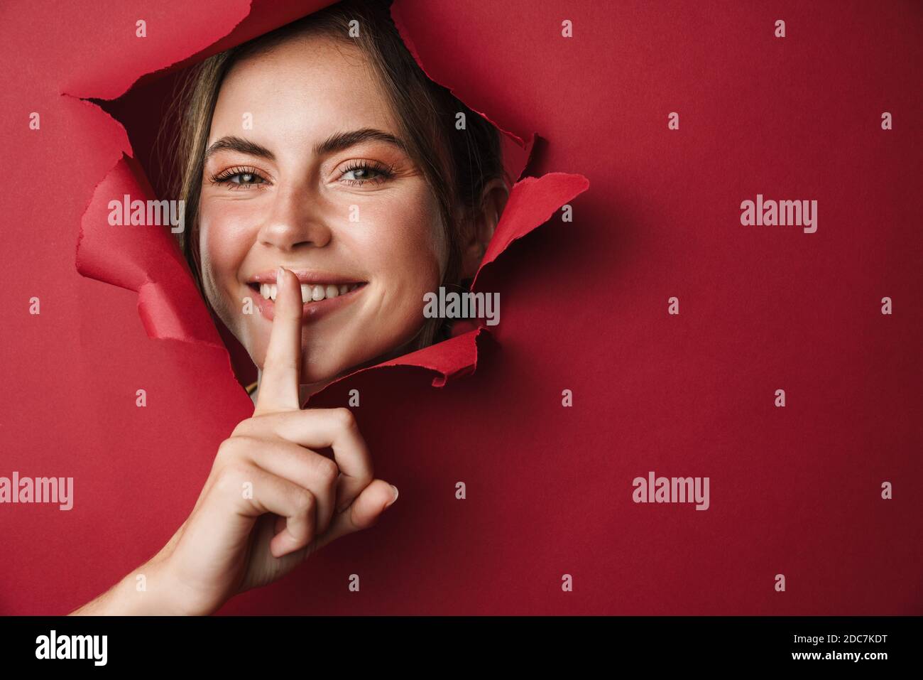 Caucasian young brunette happy woman gesturing silent sign with finger ...