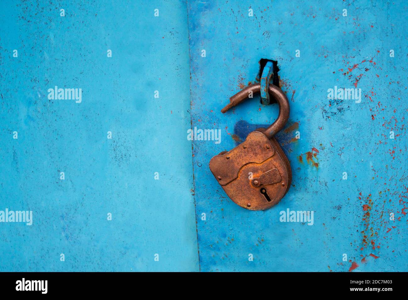 Old rusty lock with a key on a blue background Stock Photo - Alamy
