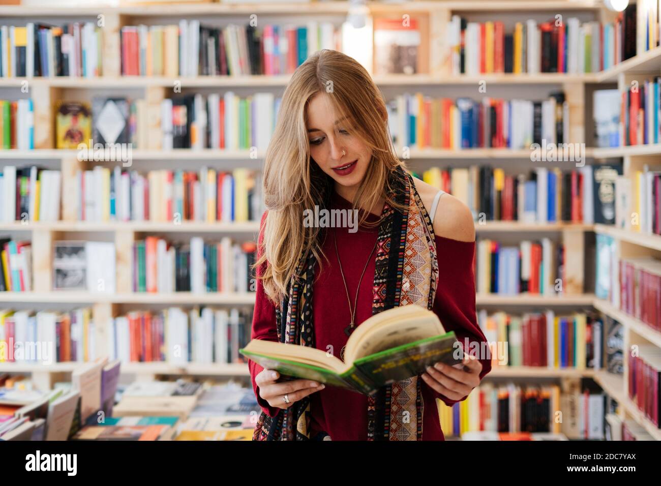 Beautiful blonde woman reading a book in a bookstore Stock Photo - Alamy
