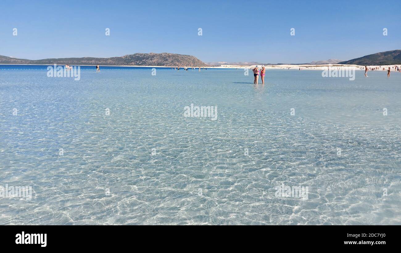 People walk in the shallow blue clear water of Lake Stock Photo - Alamy