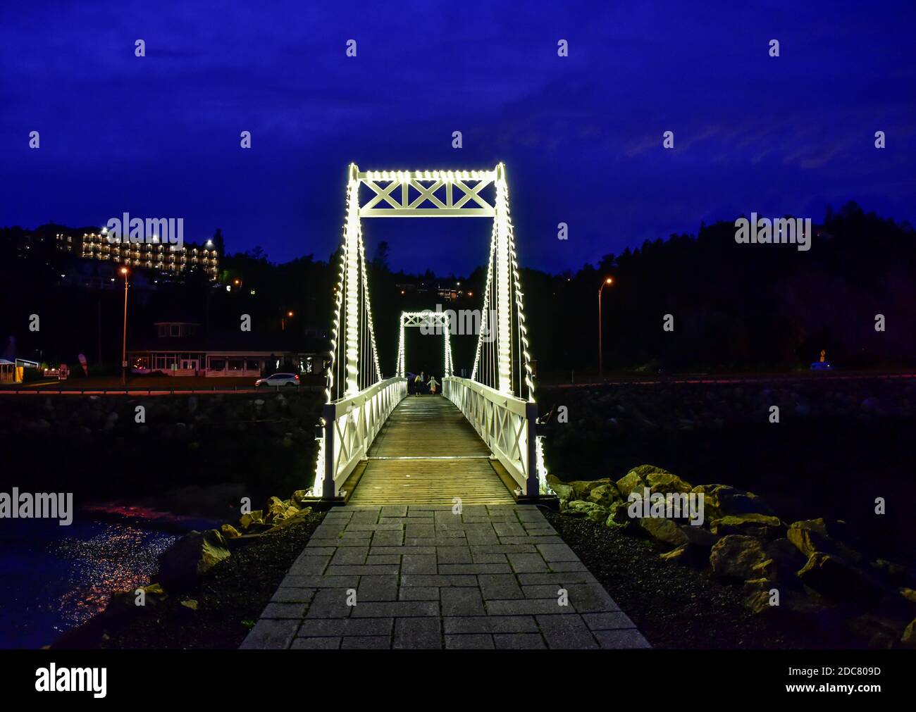 boardwalk footpath bridge lit up at night along harbor shore Stock ...