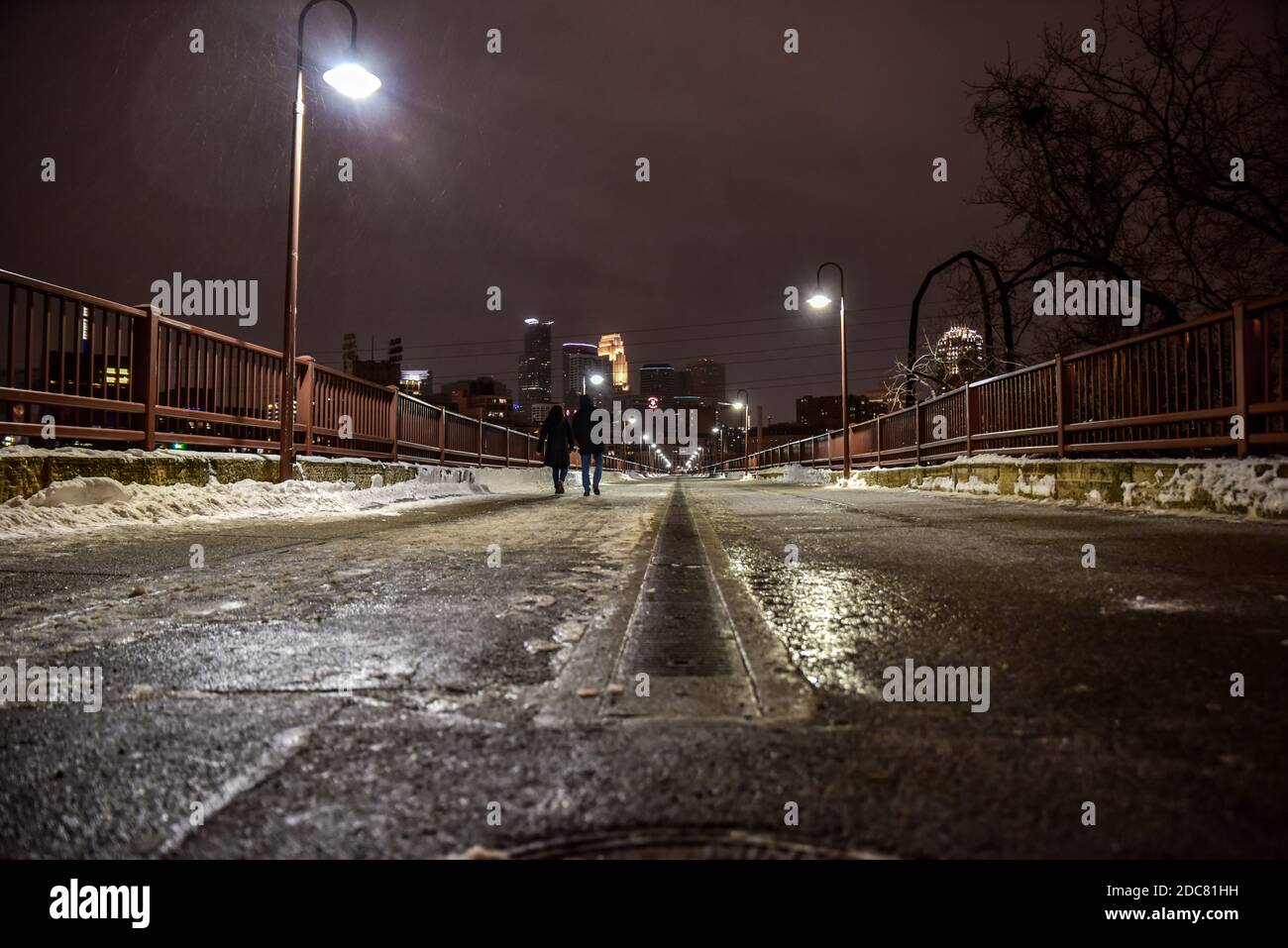 walking at night across urban city bridge over the river with skyline ...