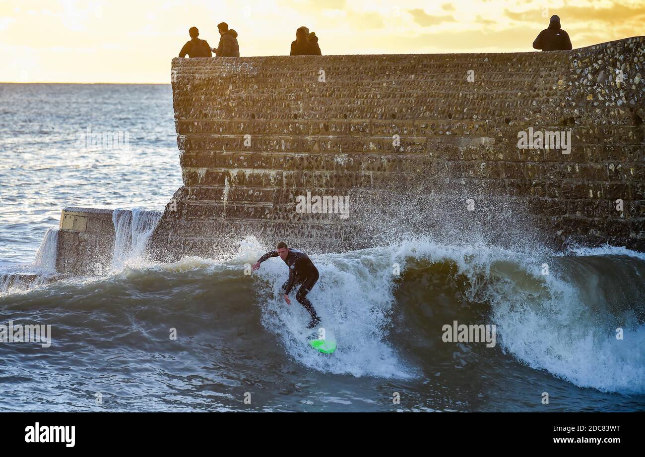 Brighton UK 19th November 2020 - A surfer catches a wave at sunset off ...