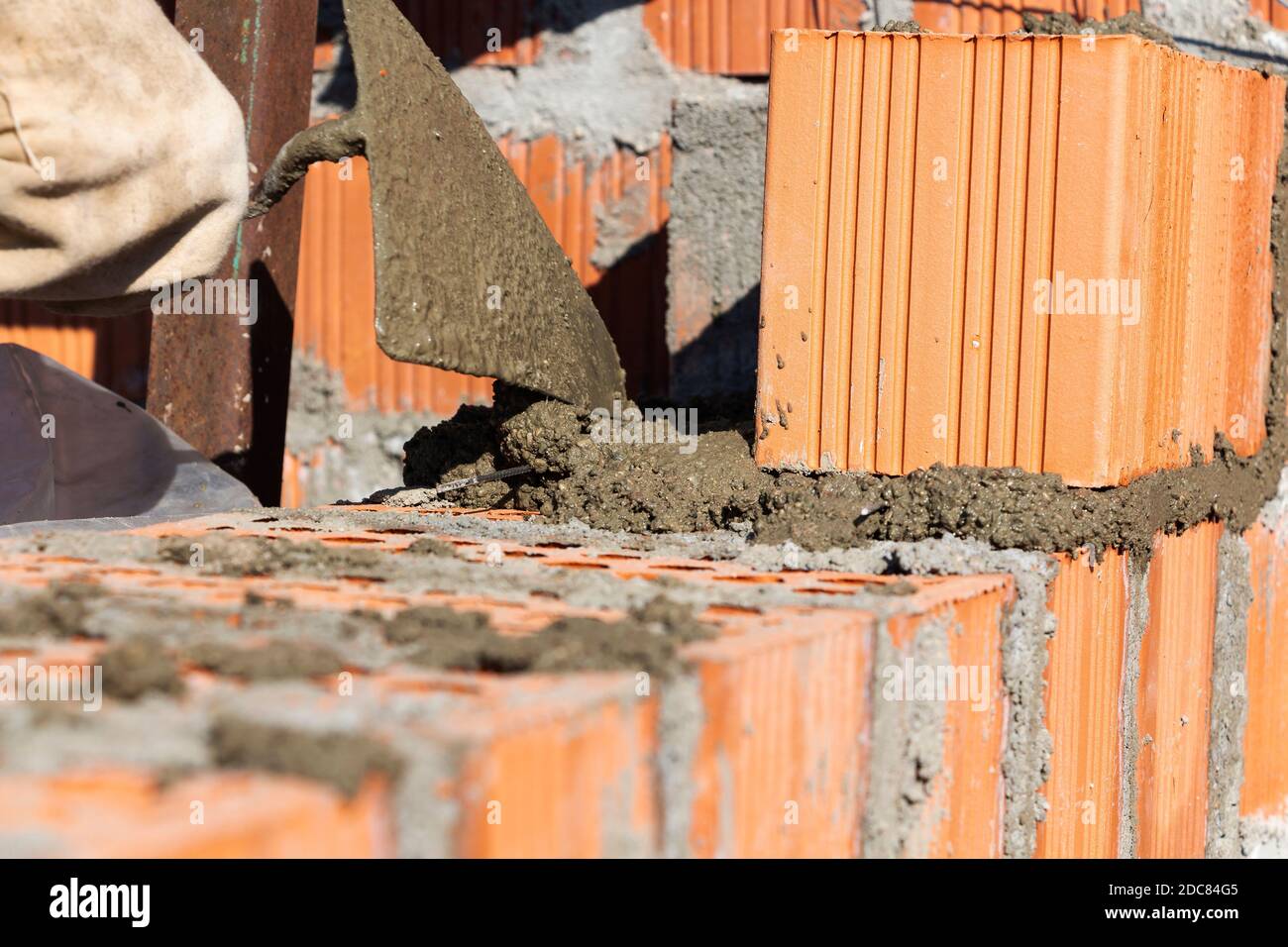Spatula and cement mortar, red brick masonry, construction concept ...