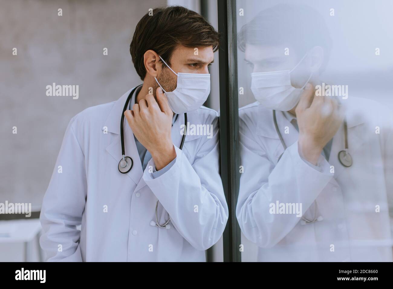 Handsome male doctor looking away with worry, frustration, tiredness ...