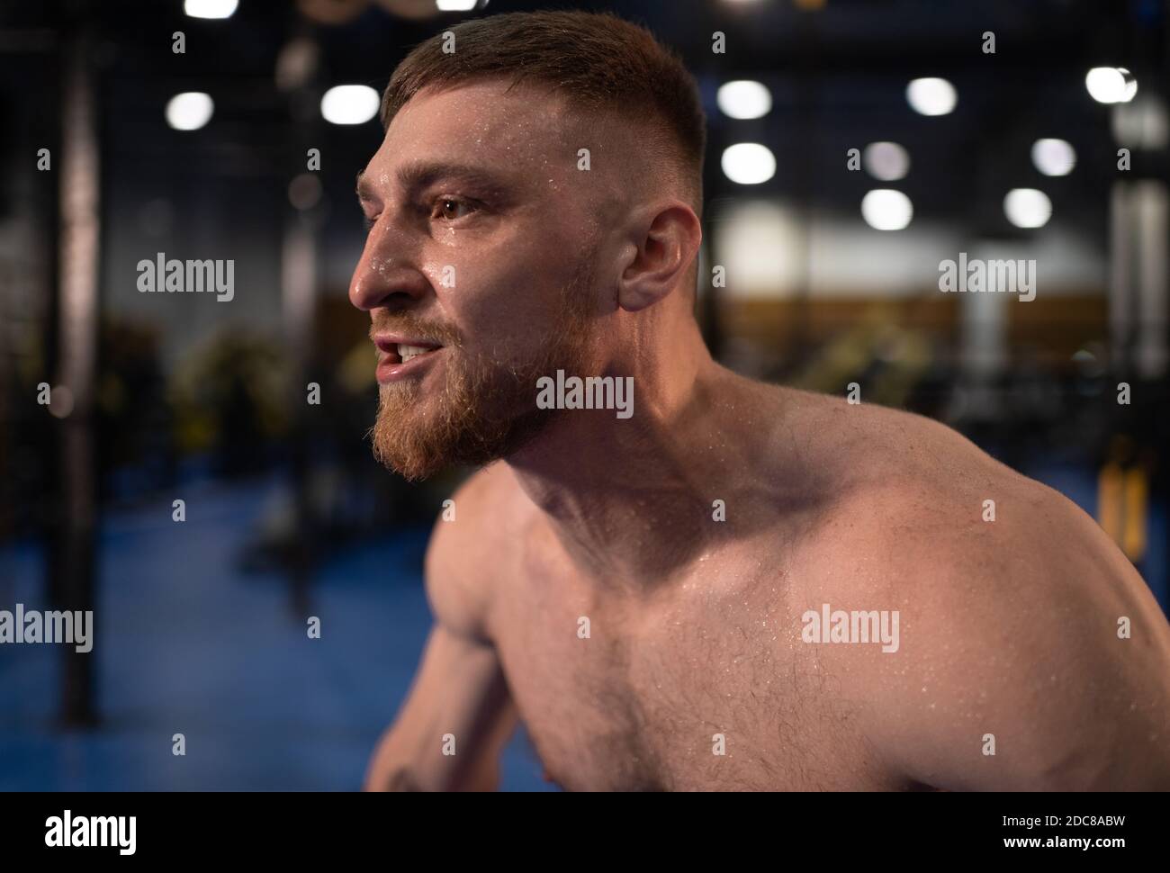 Focused male athlete doing snatch exercise during weightlifting workout ...