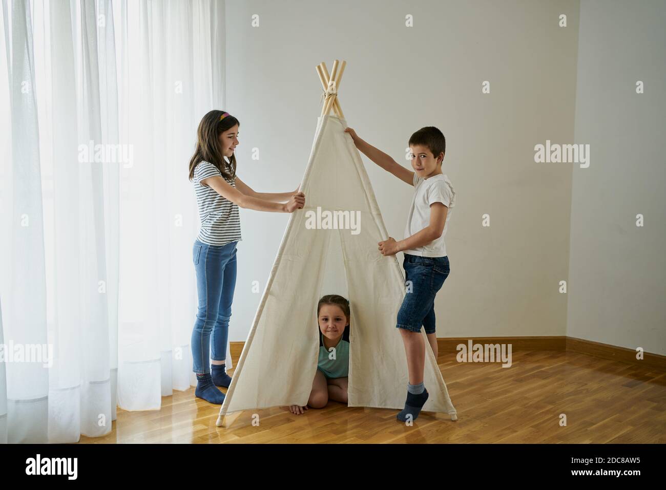 Children setting up a teepee tent inside their house. Childhood concept ...