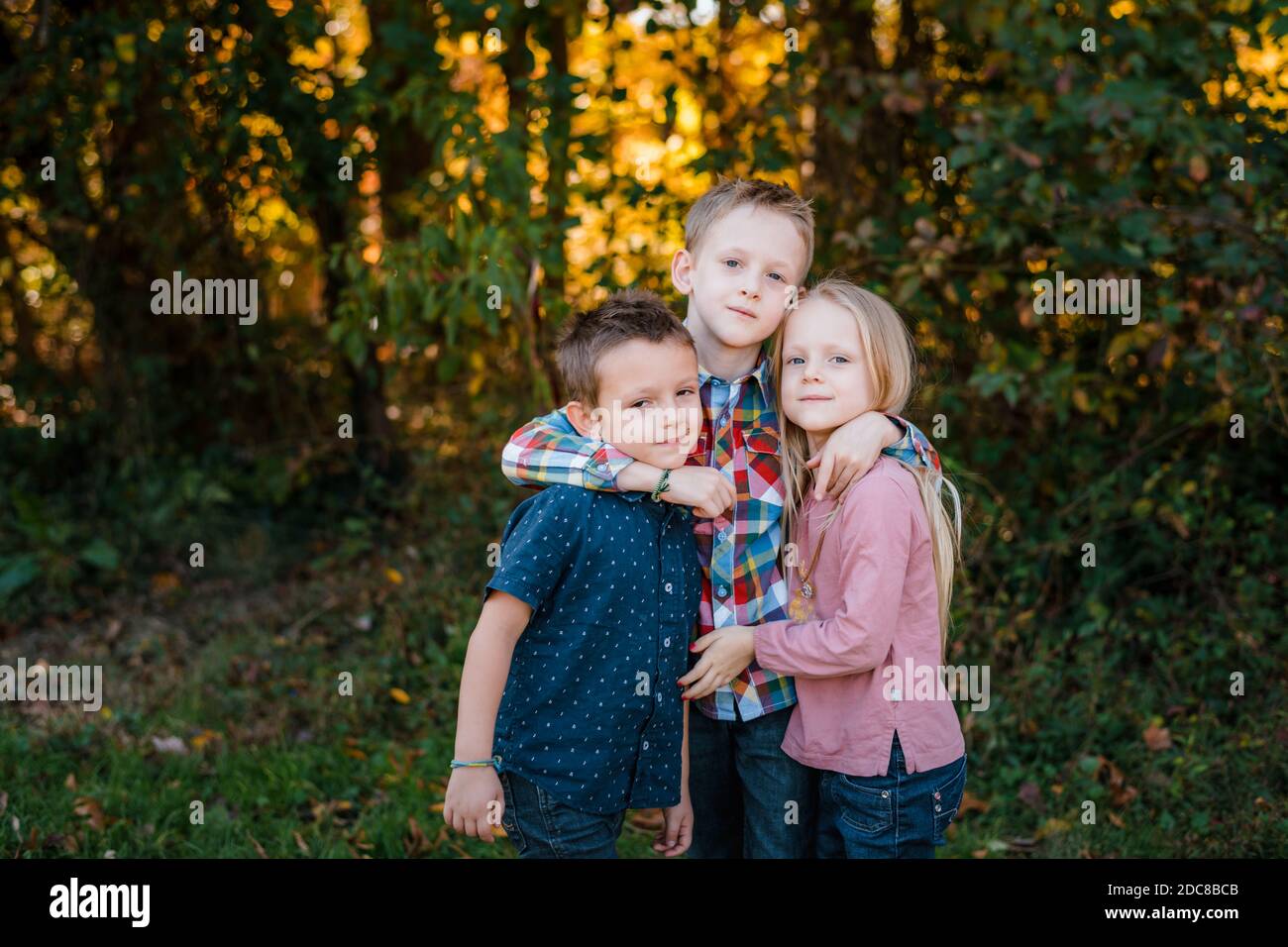 Brother embracing siblings outdoors in nature family portrait Stock ...