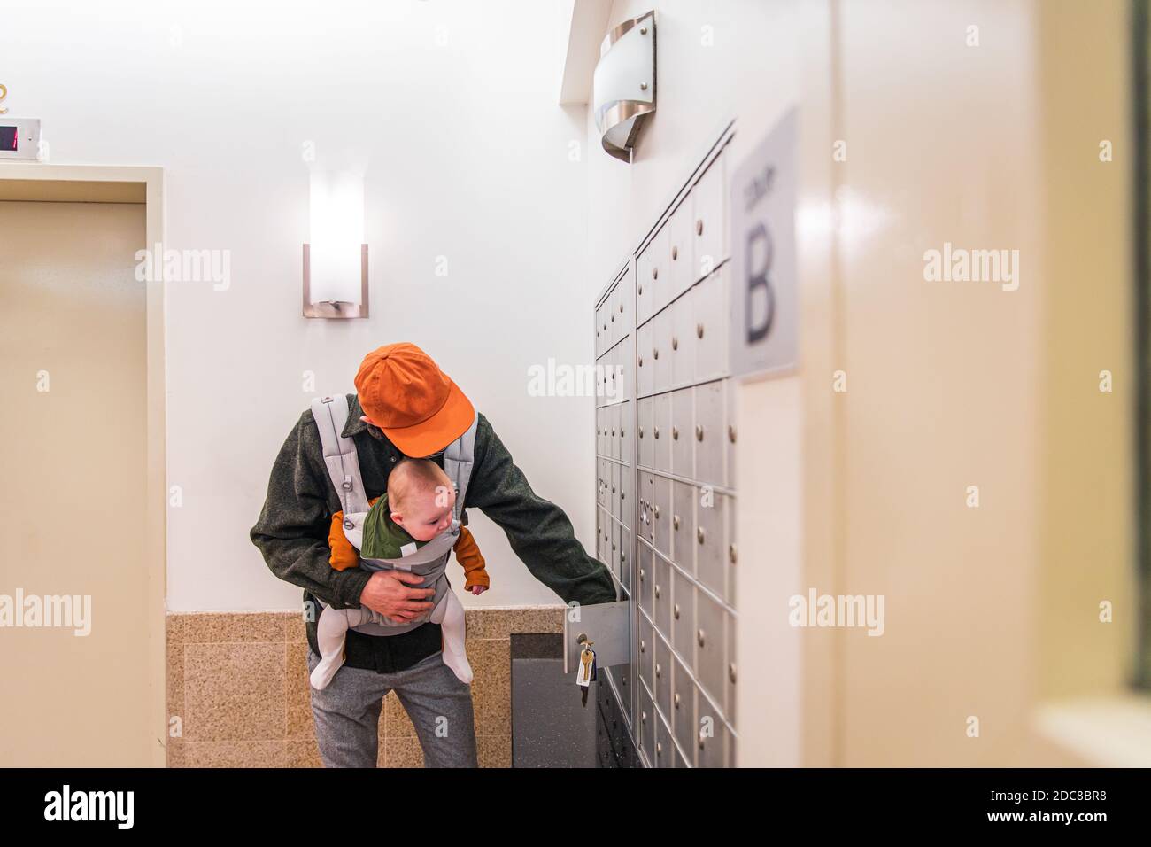 Father carrying daughter in carrier opening locker in room while during ...