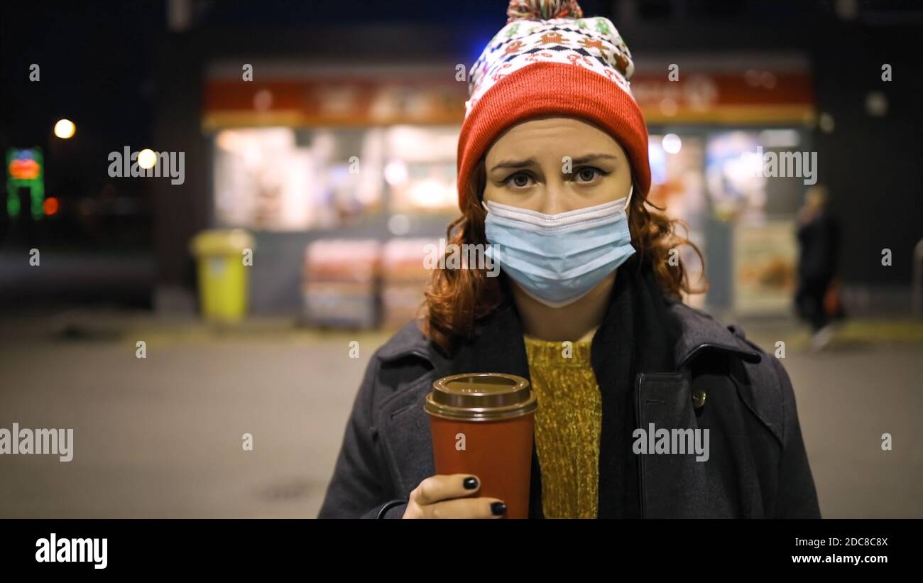 Tired young woman in medical mask and Xmas hat holds coffee cup Stock ...