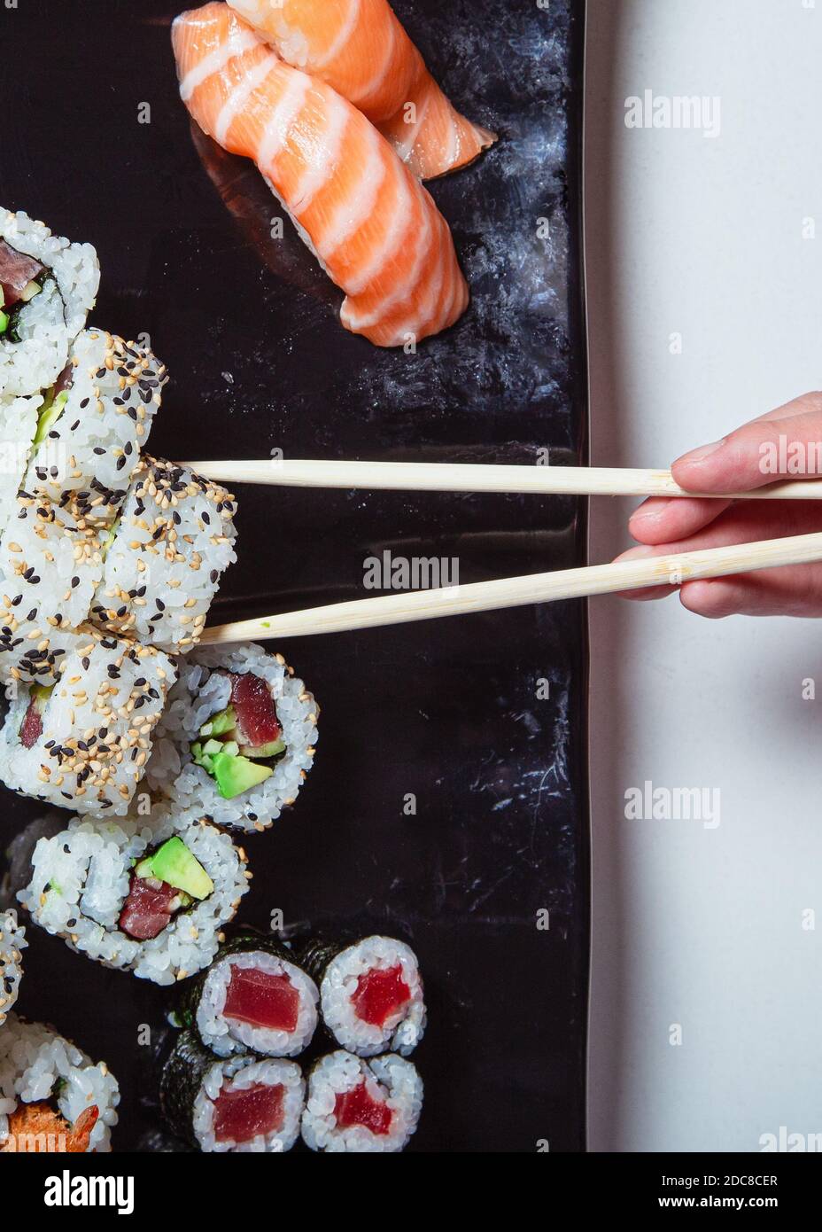 Top view of woman's hand holding sushi sticks. Sushi rolls laid out on ...