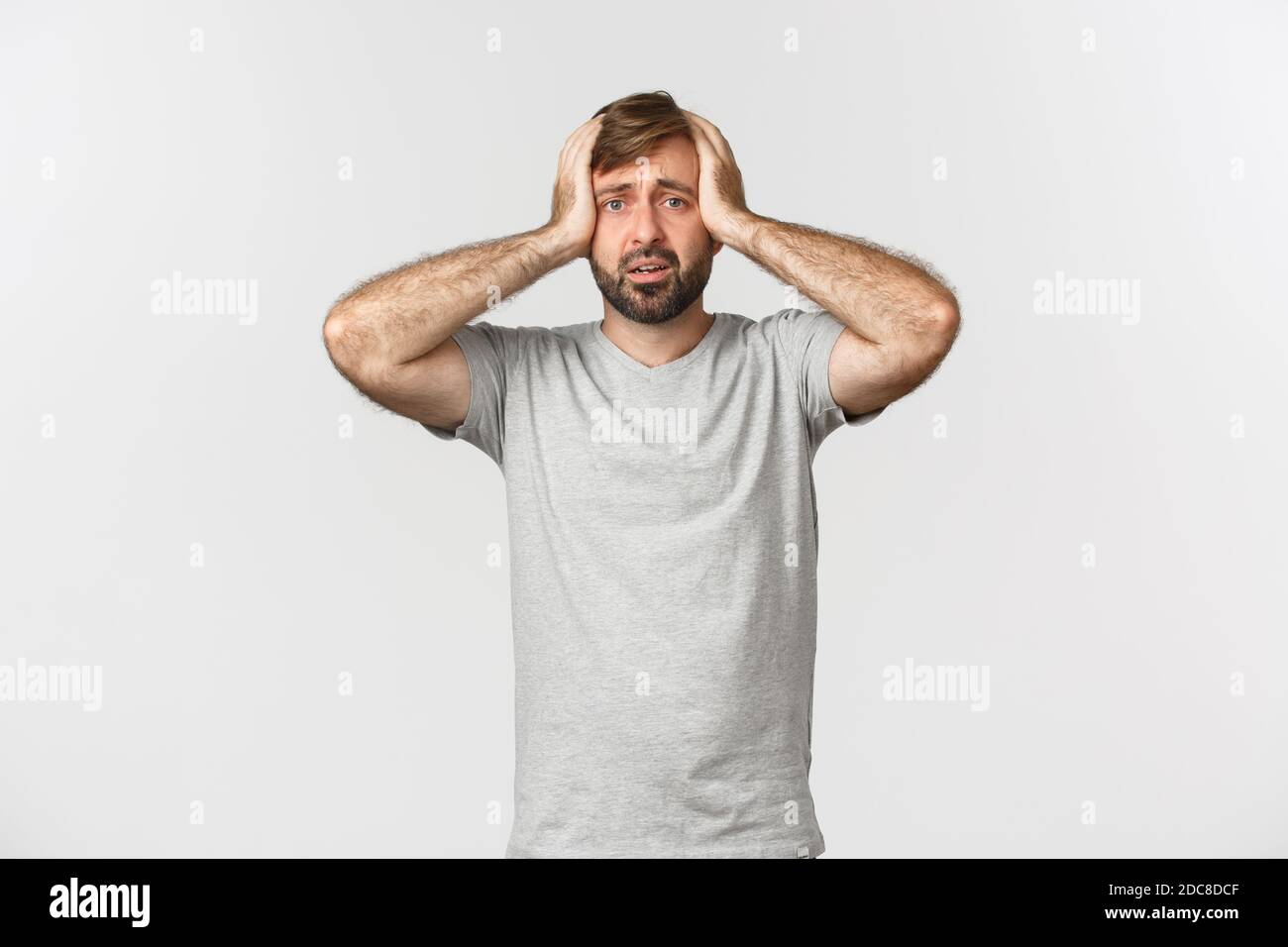 Portrait of troubled man having panic, holding hands on head and ...