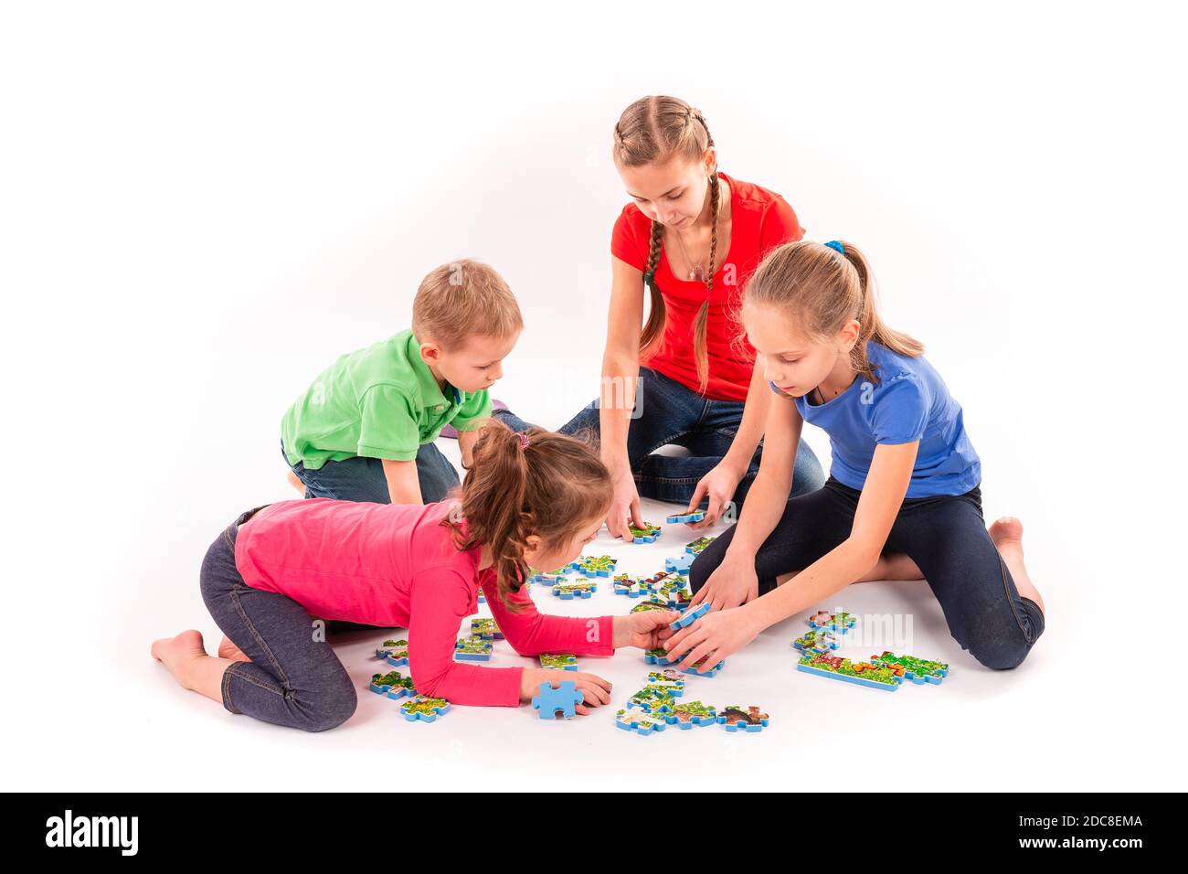 Kids of different age solving jigsaw puzzle together. Teamwork, working ...