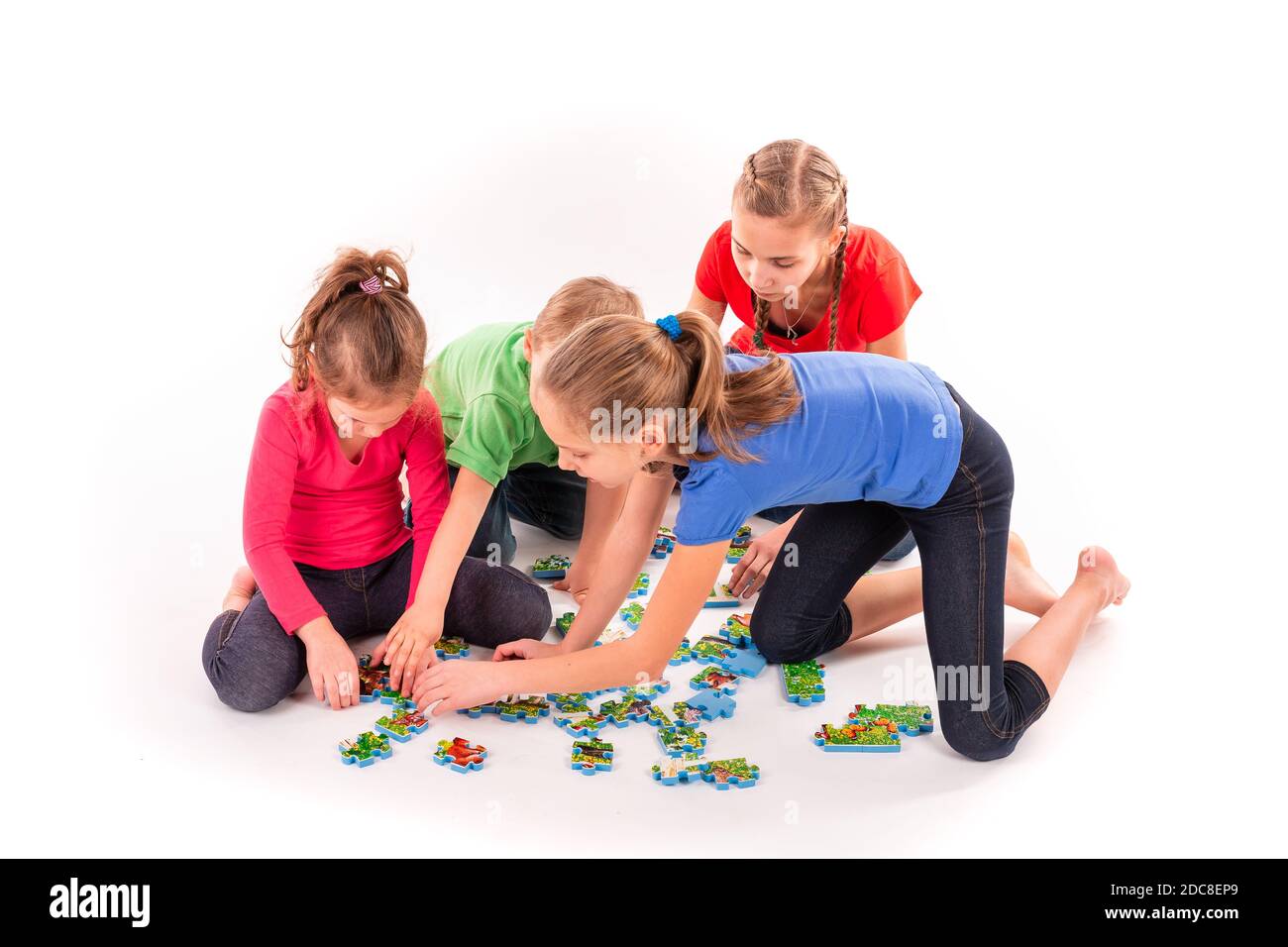 Kids of different age solving jigsaw puzzle together. Teamwork, working ...