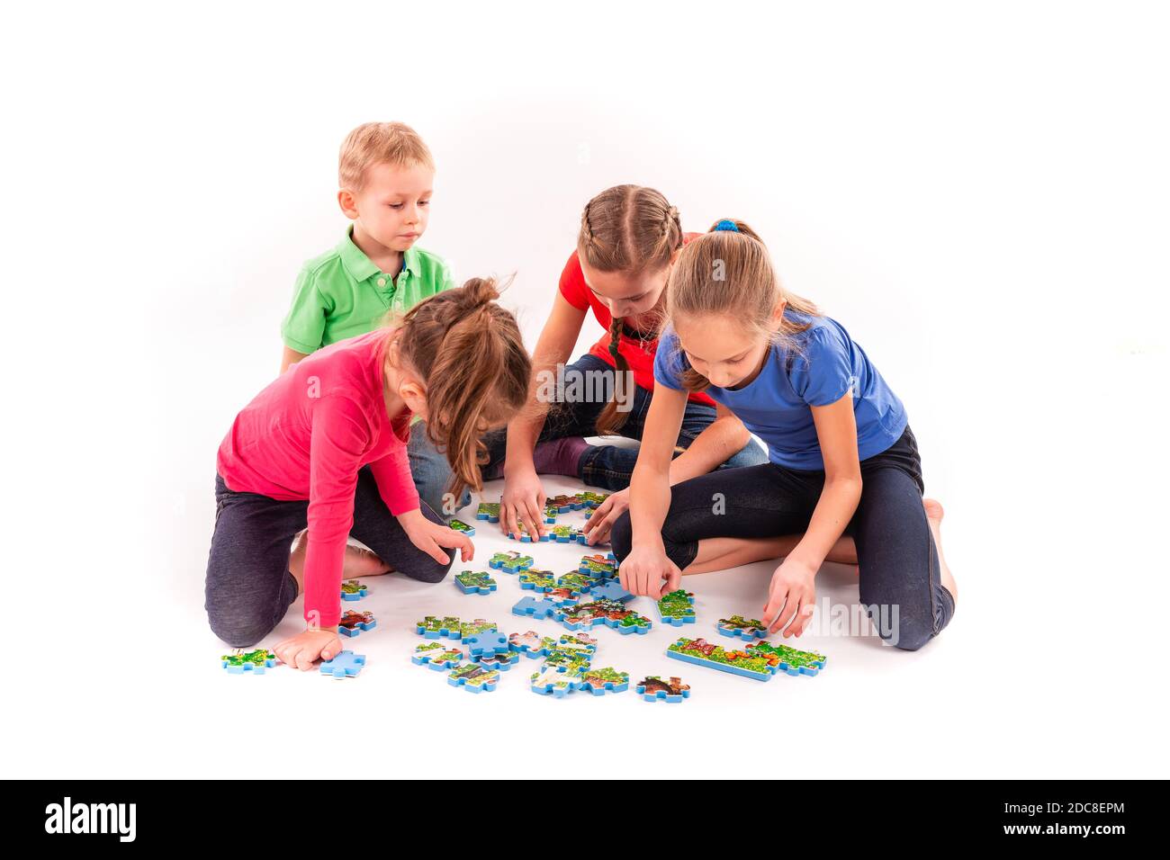 Kids of different age solving jigsaw puzzle together. Teamwork, working ...