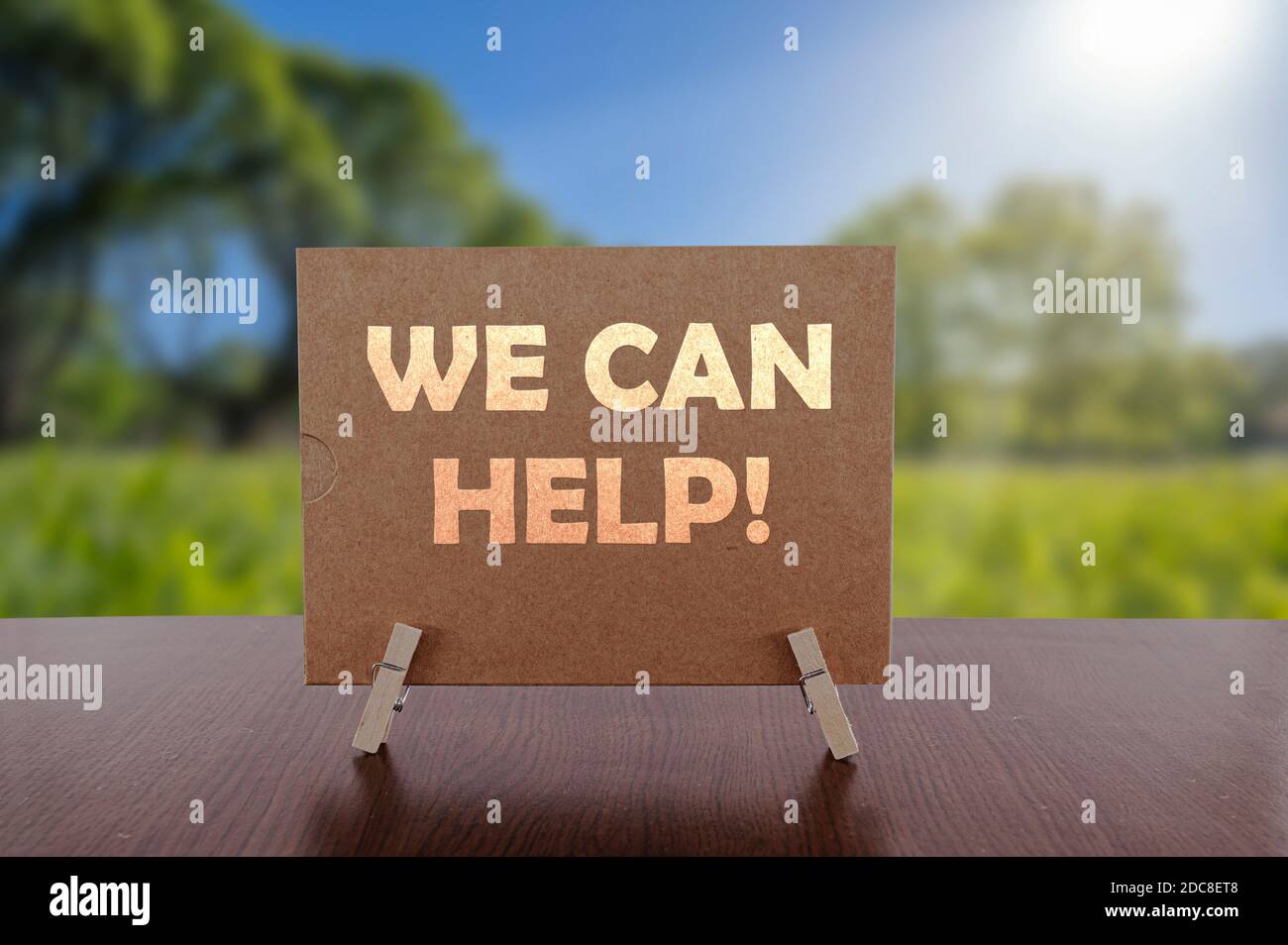 We can help card on the table with sunny green park background Stock ...