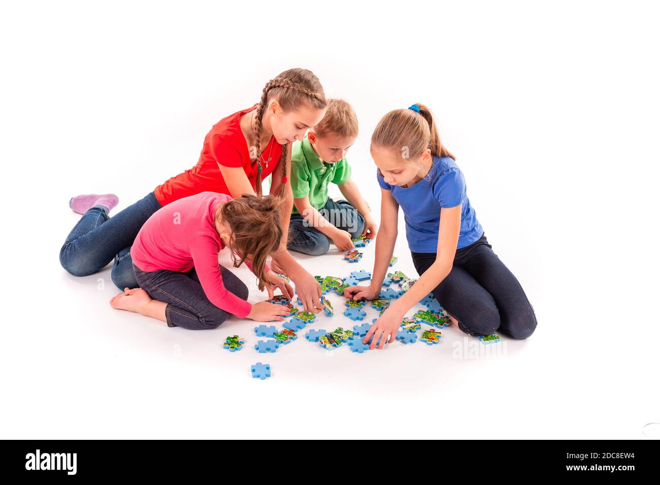 Kids of different age solving jigsaw puzzle together. Teamwork, working ...