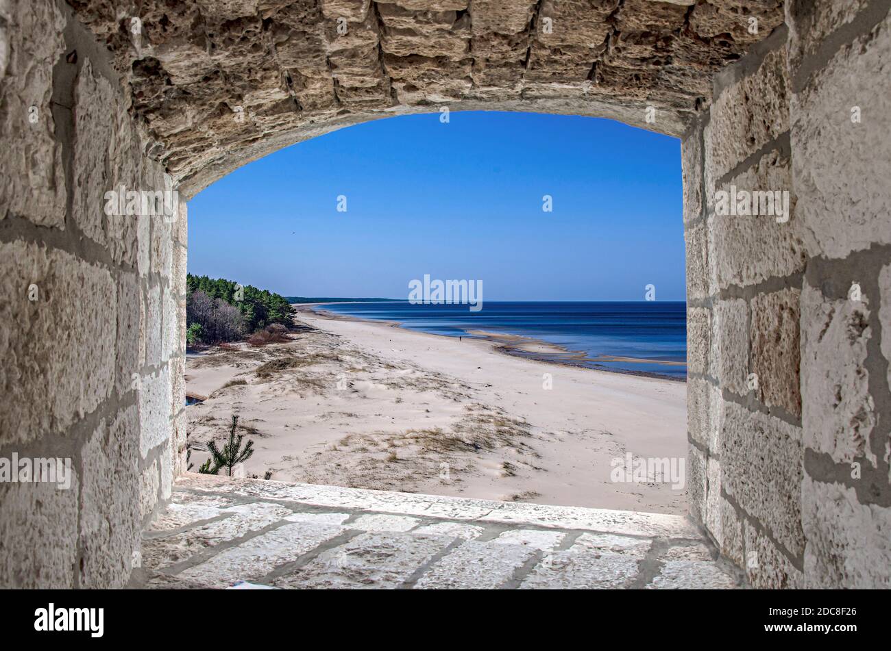 View from stone window of beach with white sand and blue sea/ocean ...