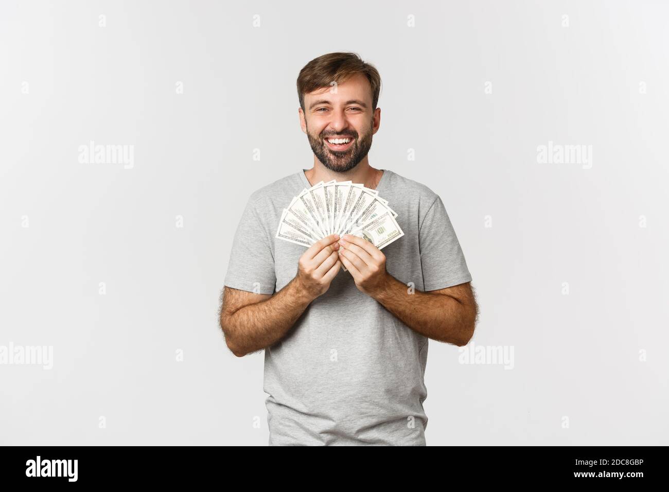Happy man smiling pleased, showing money, standing over white ...