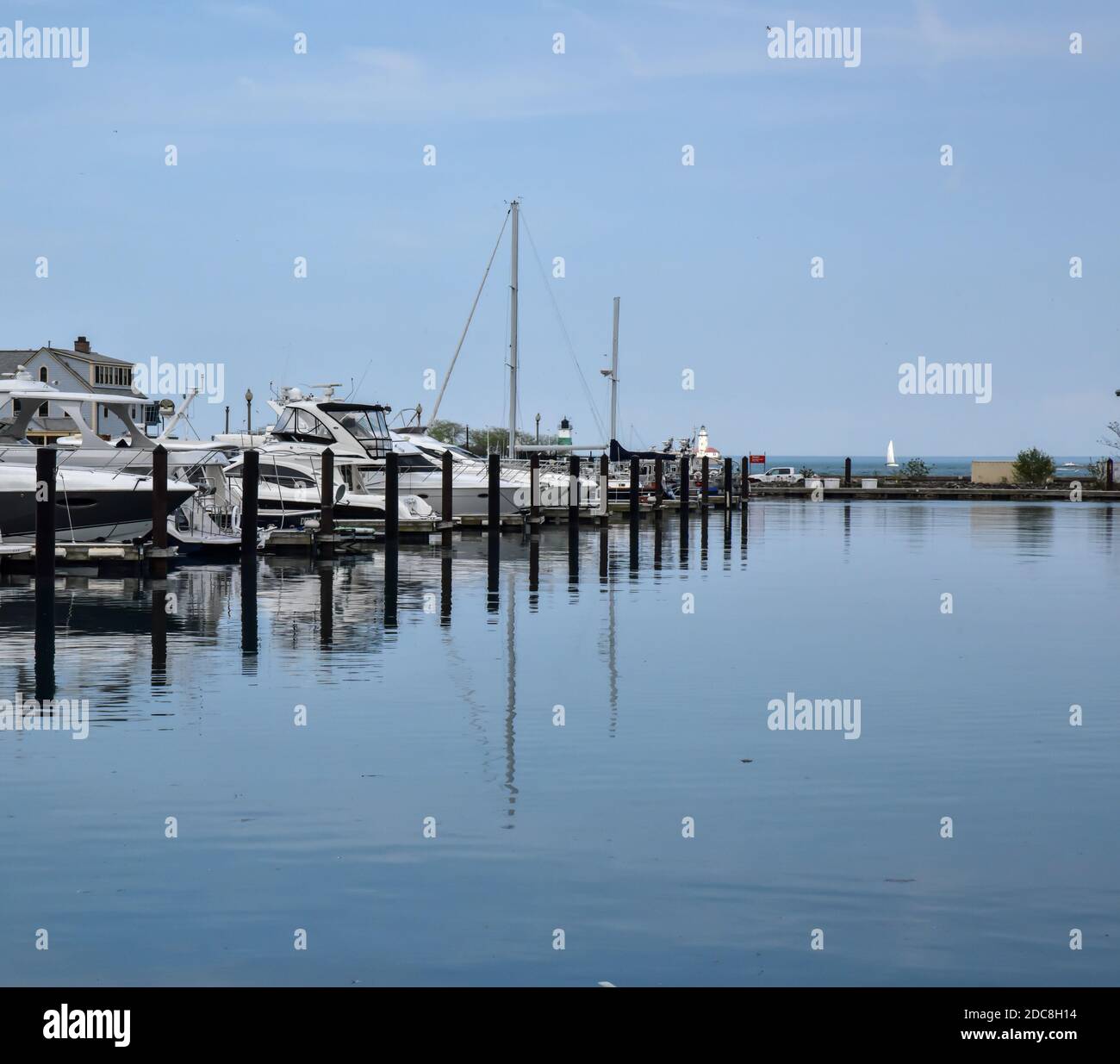 Sailboat docked in the calm harbor during the summer un der blue sky ...