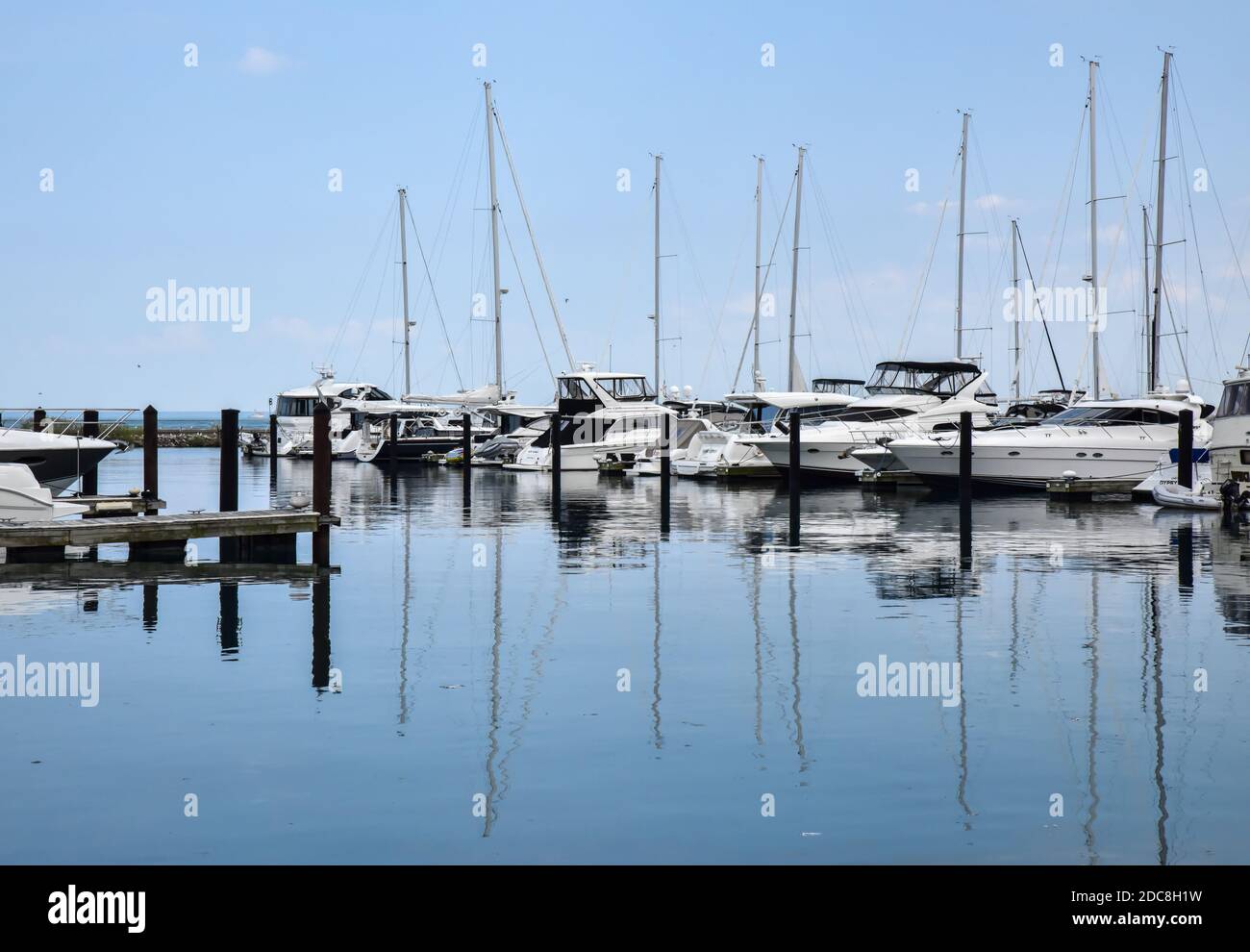 Sailboat docked in the calm harbor during the summer un der blue sky ...