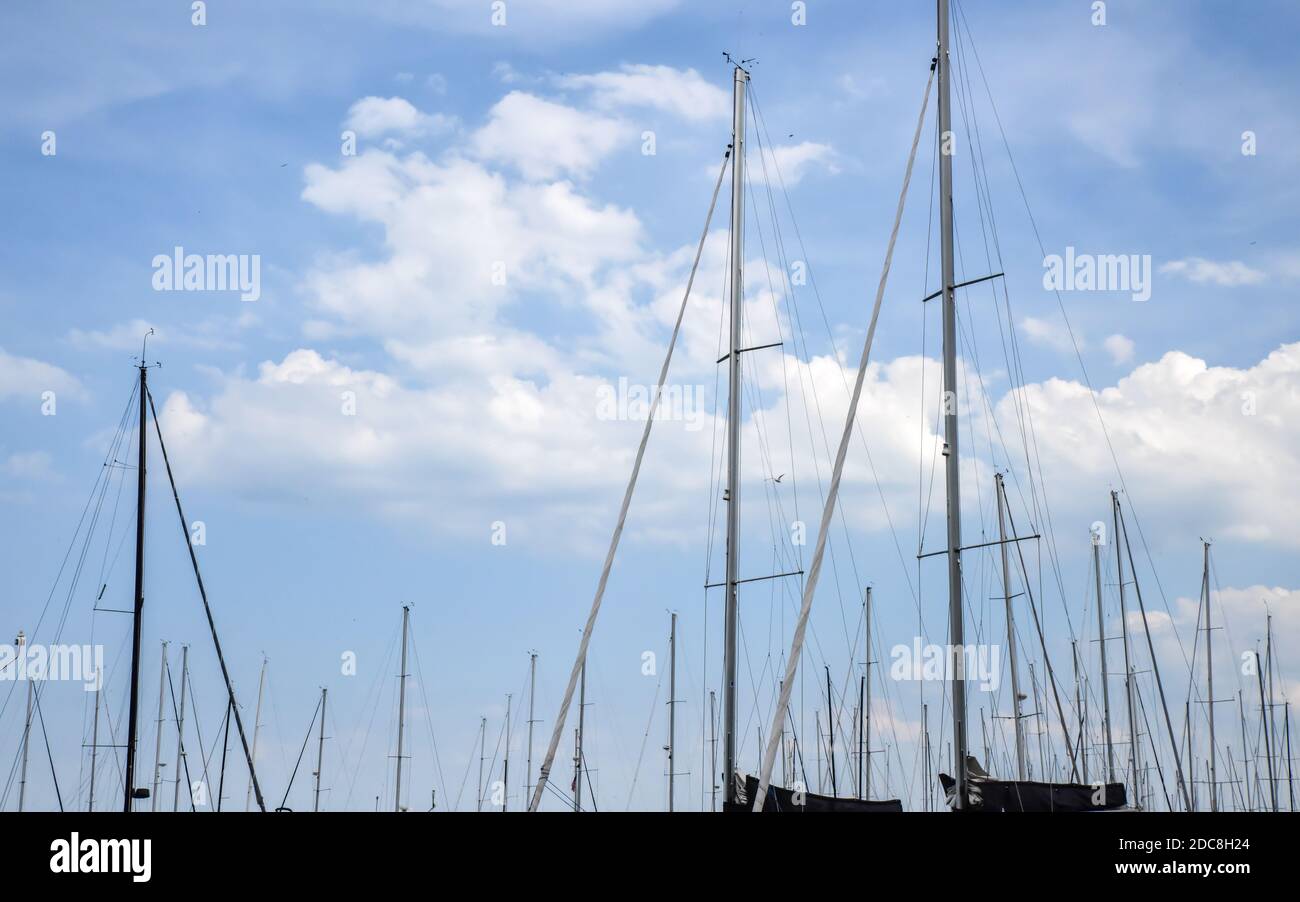 Sailboat docked in the calm harbor during the summer un der blue sky ...