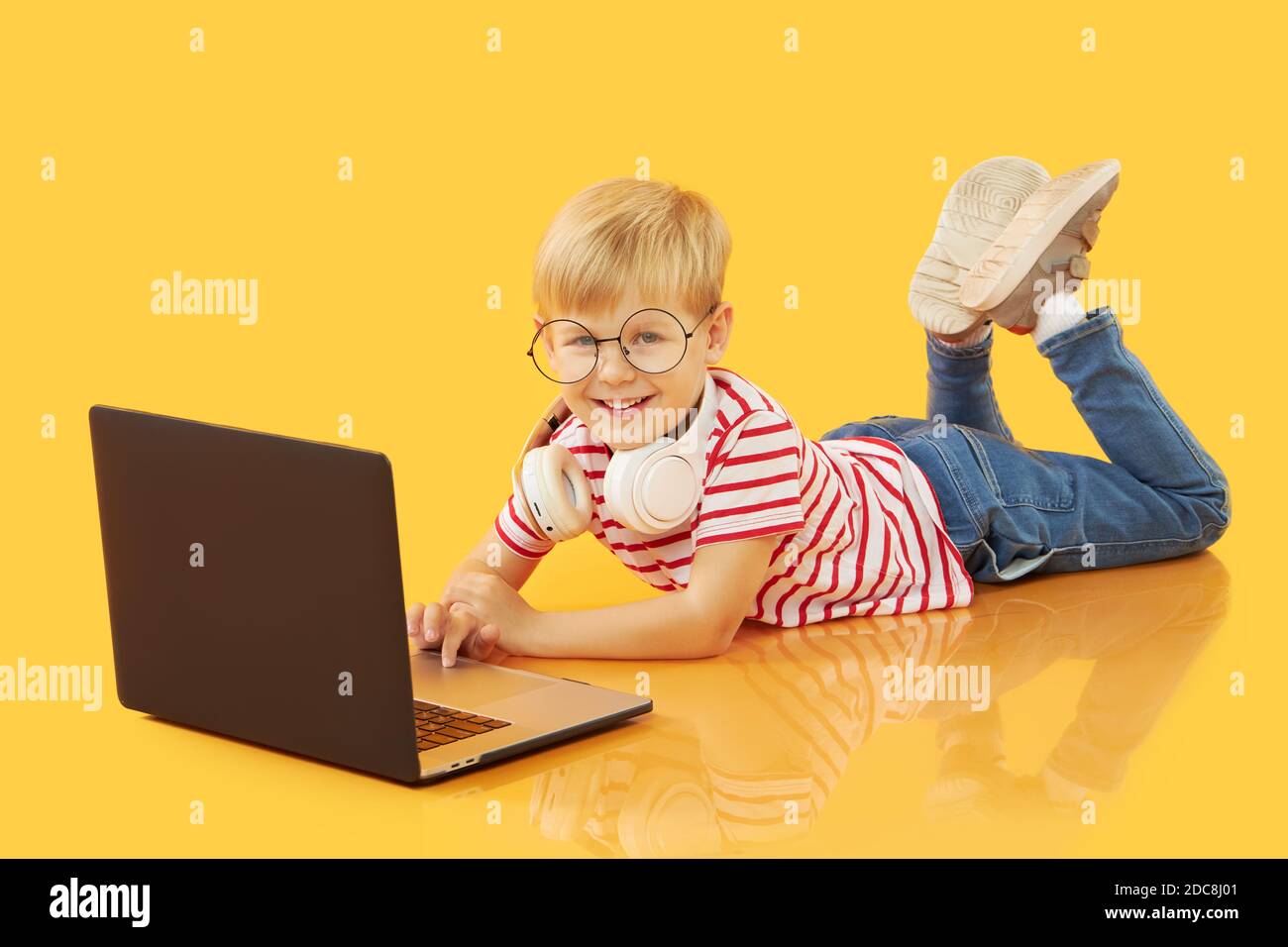 Litttle child boy using laptop on yellow background. Education, online ...