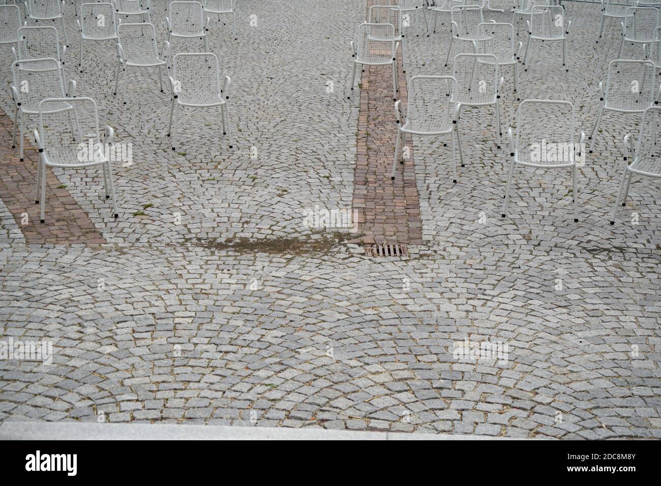 A top view closeup of white metal chairs placed on the pavement outside ...