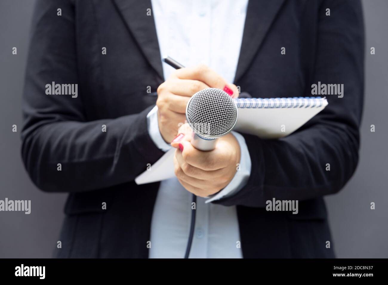 Reporter at press conference or media event, writing notes, holding ...