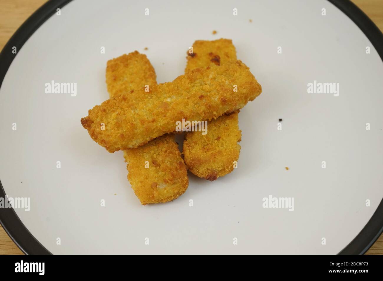 Three Cod fish fingers on a plain plate Stock Photo - Alamy