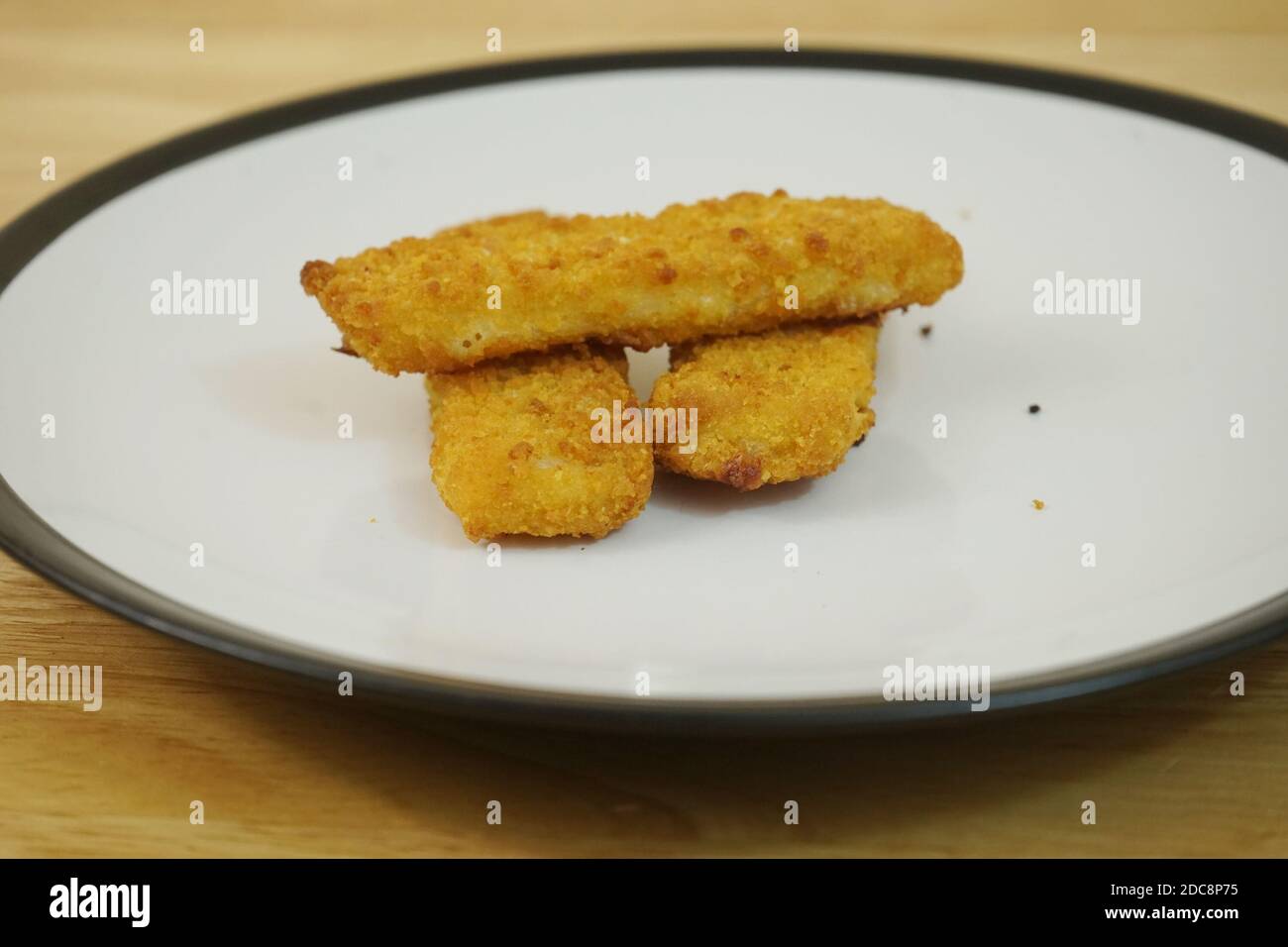 Three Cod fish fingers on a plain plate Stock Photo - Alamy
